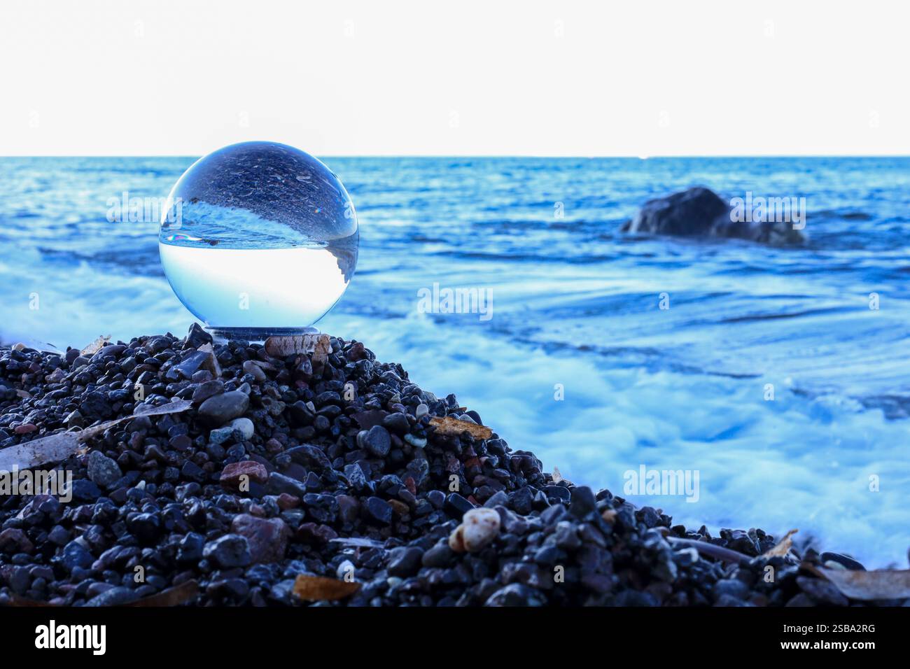 lensball resting on a rocky beach captures an inverted image of the ...