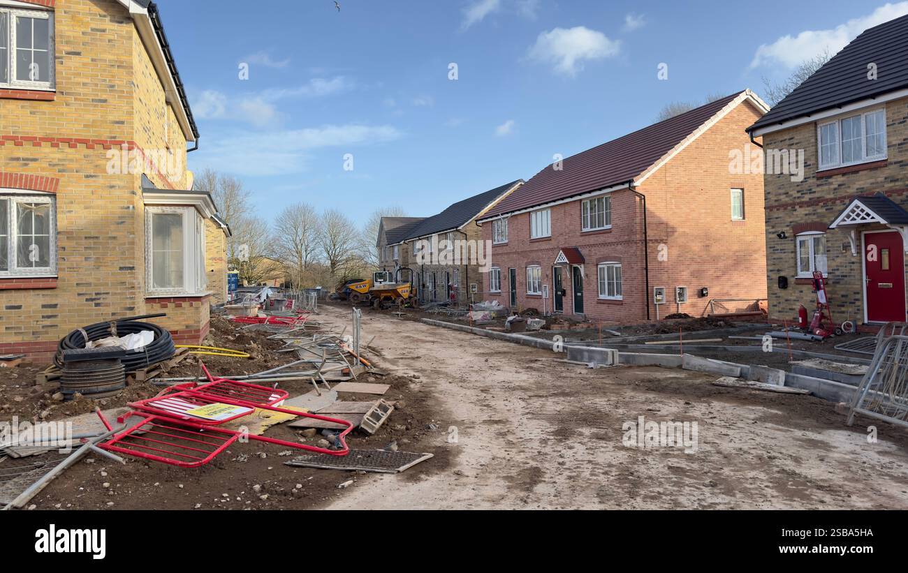 Newly constructed brick houses line a muddy street, still under ...