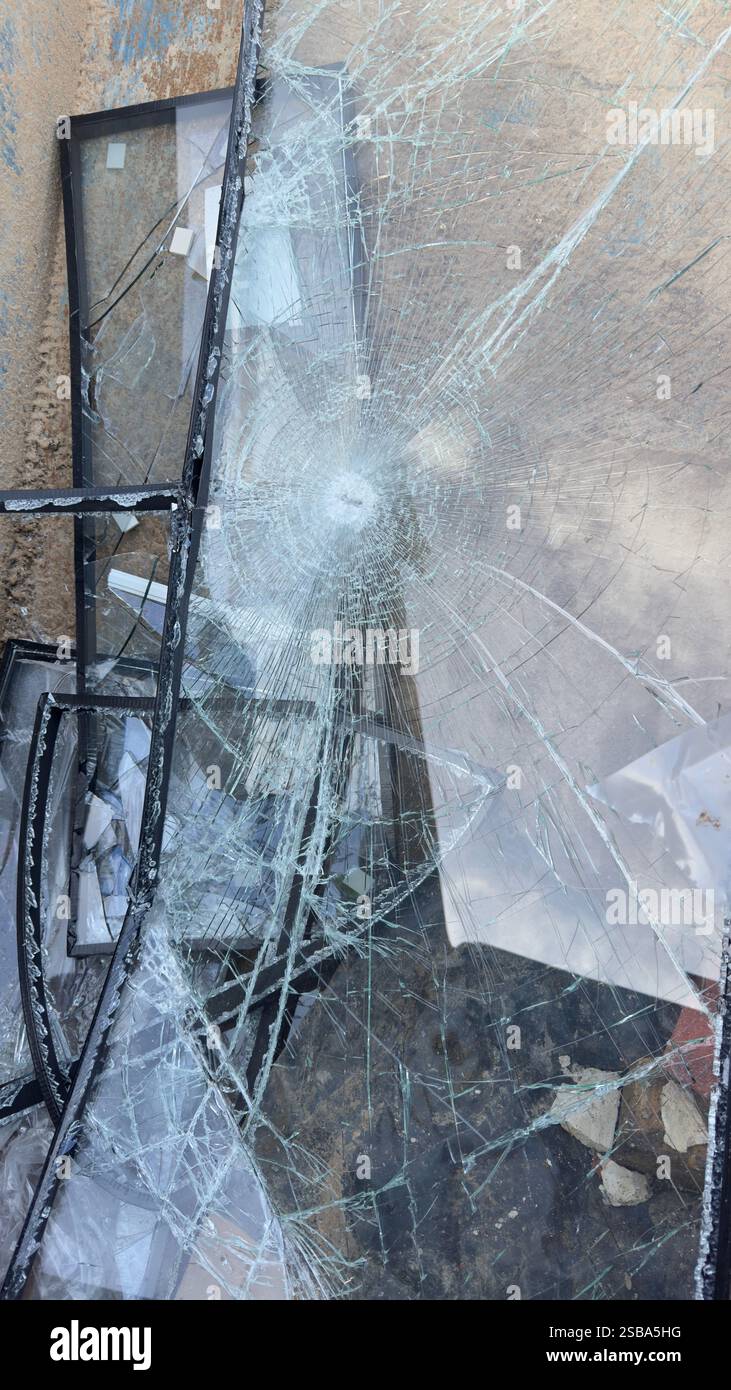 Shattered glass panes with black frames, exhibiting a central impact ...