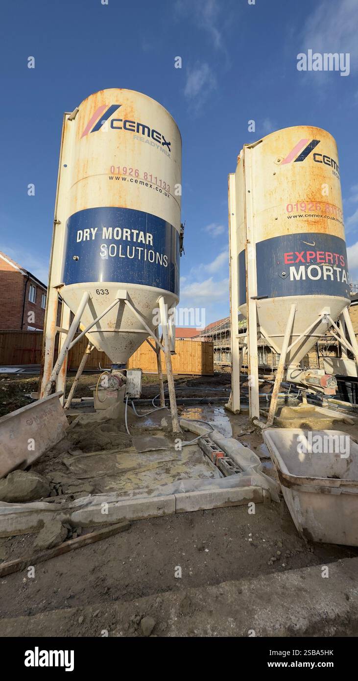 Two weathered Cemex Ready Mix dry mortar silos stand on a construction ...