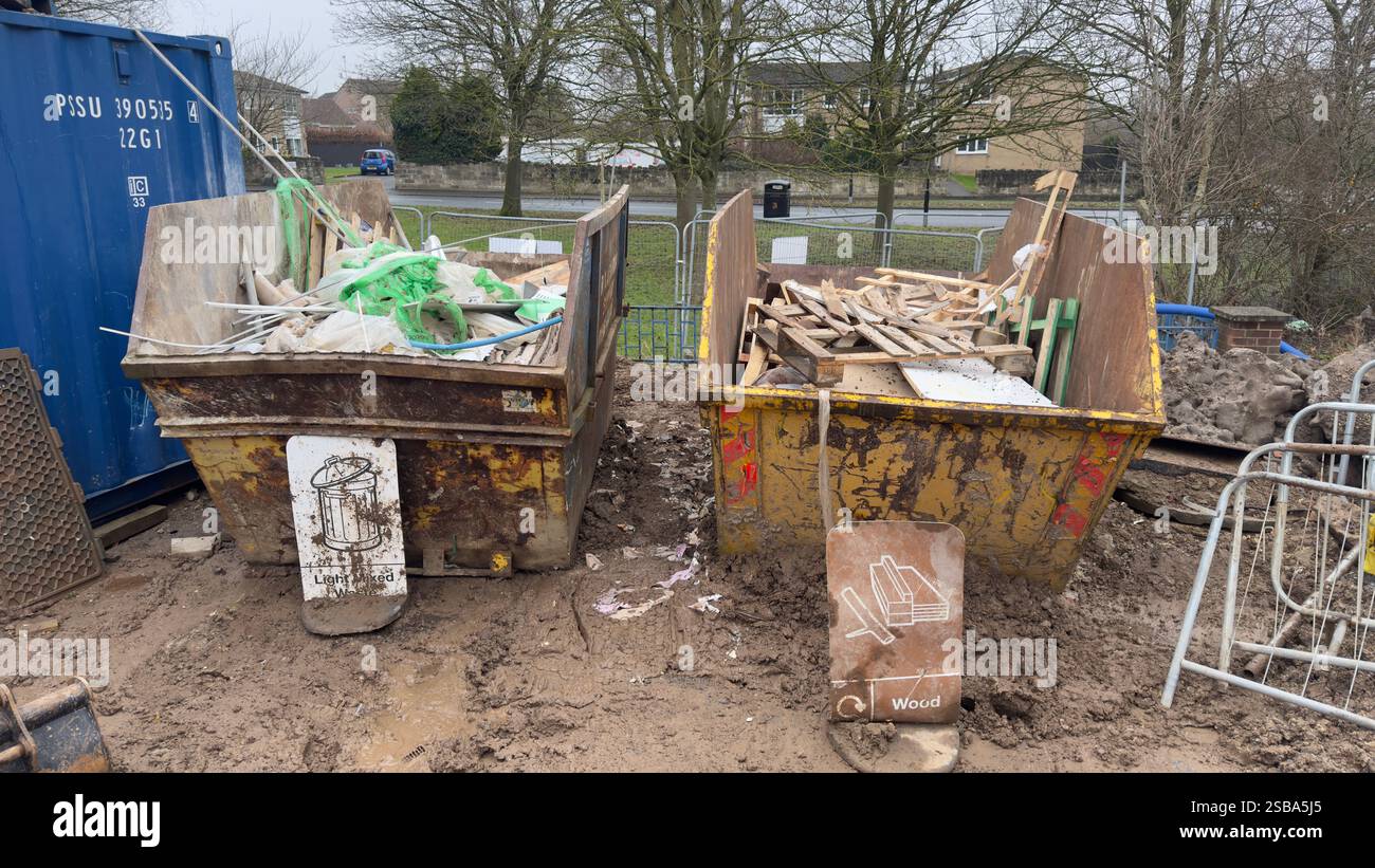 Two rusty yellow construction dumpsters filled with debris sit on muddy ...