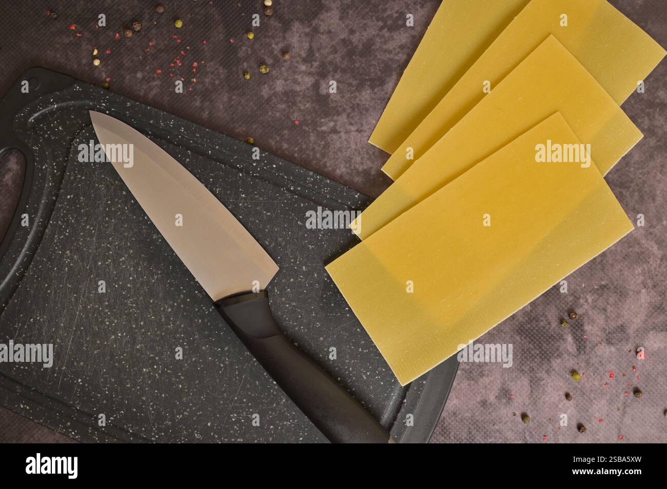 Top view knife and lasagne pasta sheets on a black kitchen cutting ...