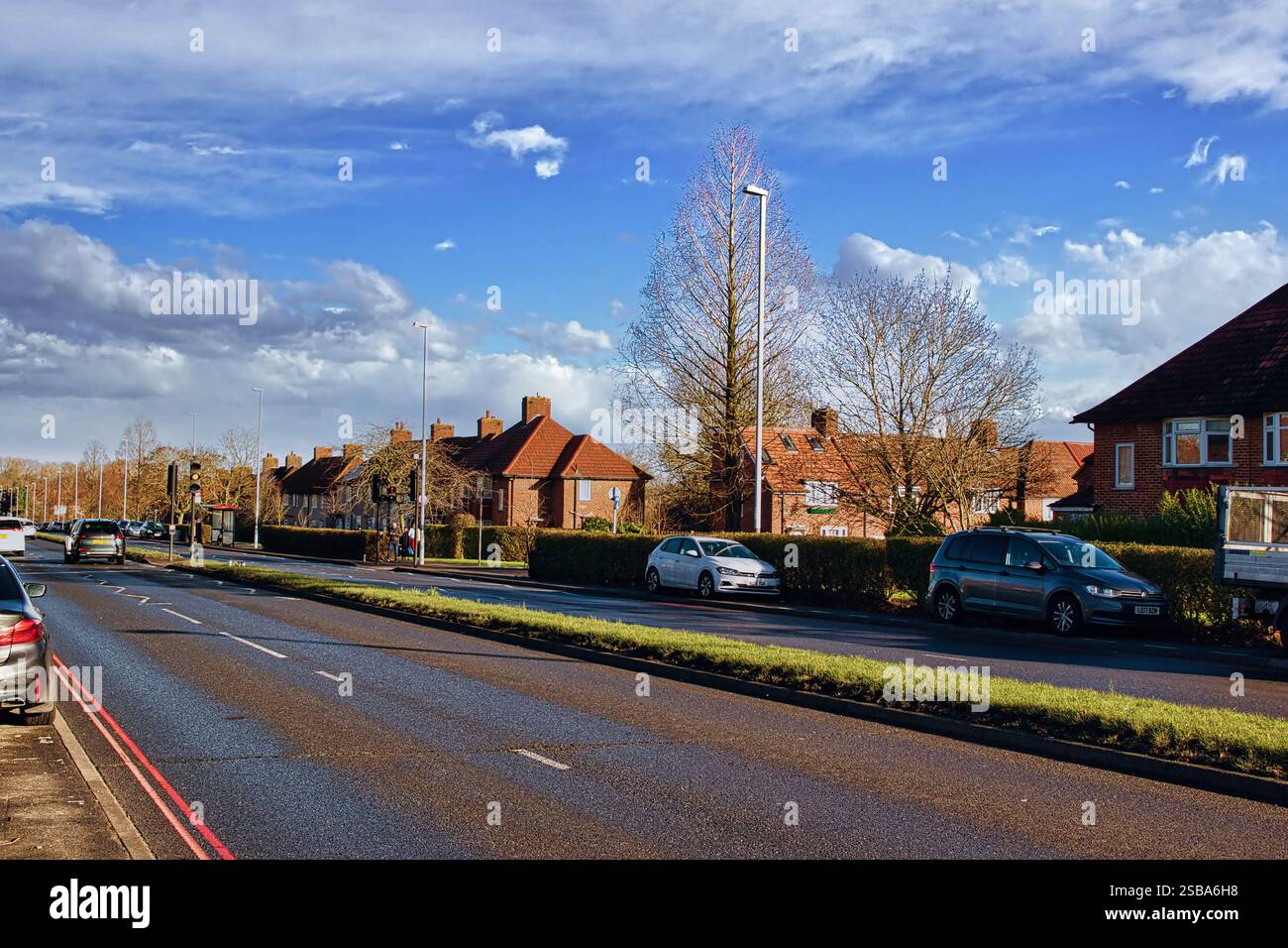 Residential street scene on a sunny day. Red brick houses line a multi ...