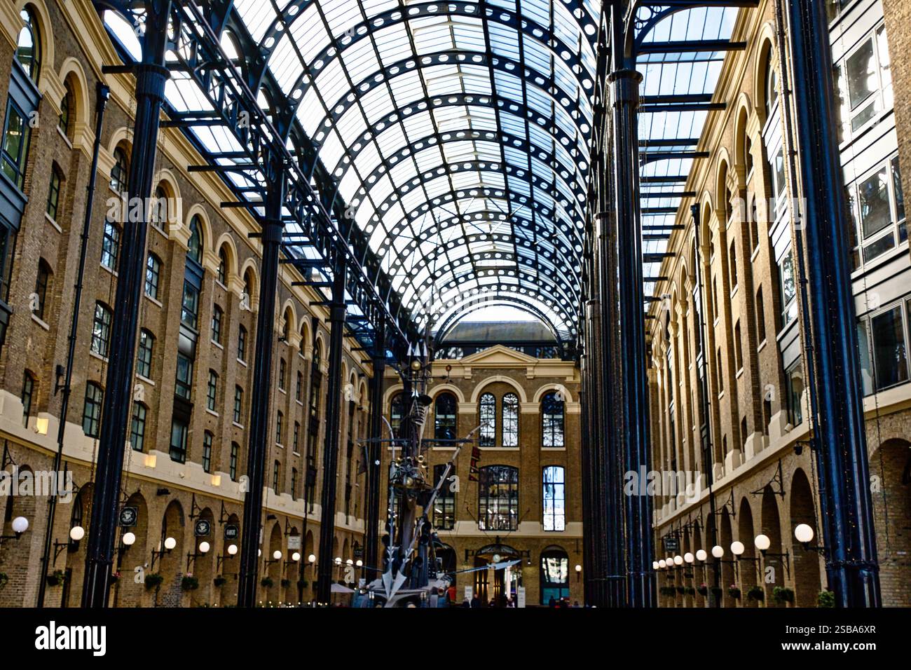 Indoor view of a modern glass-roofed arcade with tall brick buildings ...