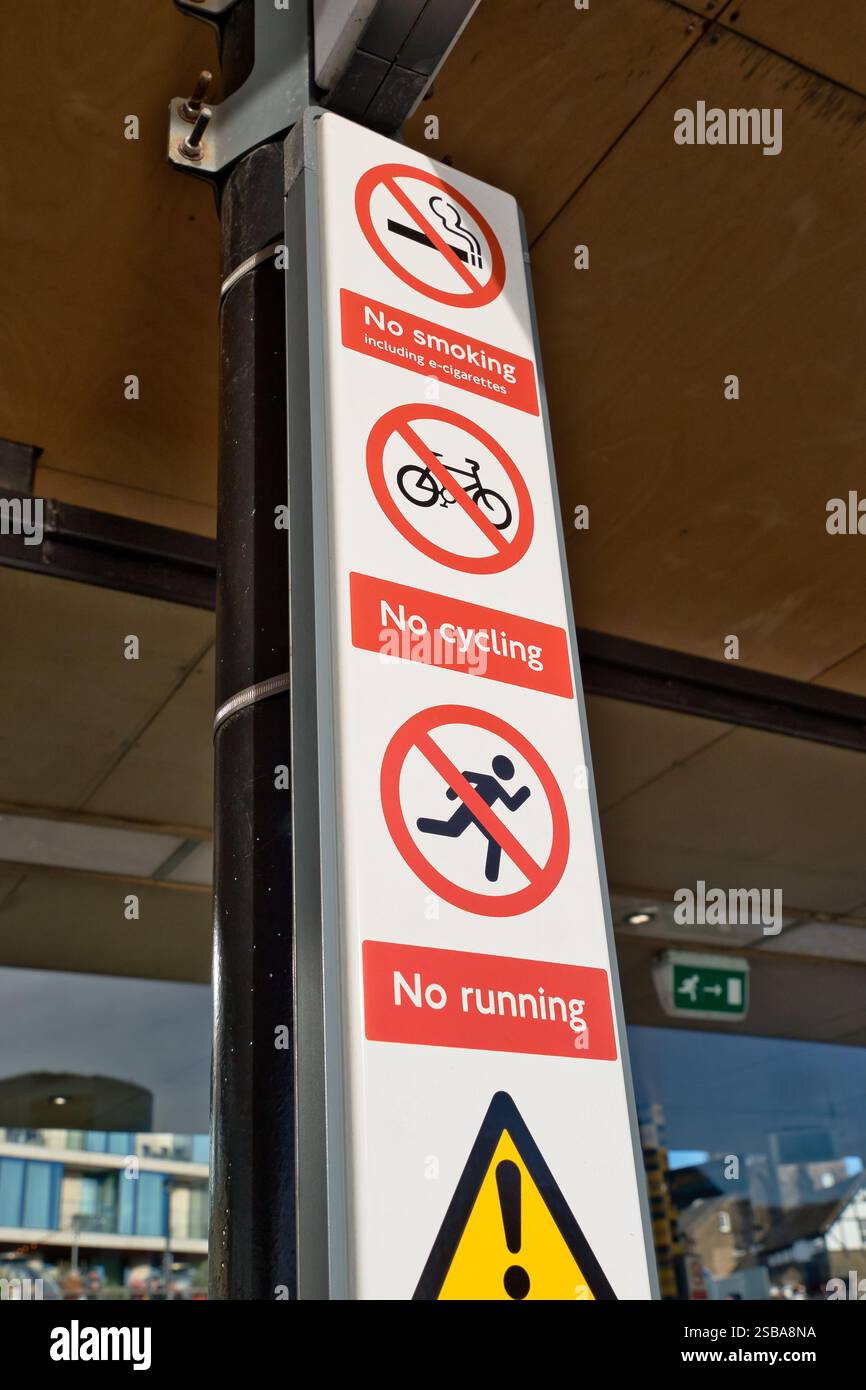 A close-up shows a white rectangular sign attached to a black pole. The ...
