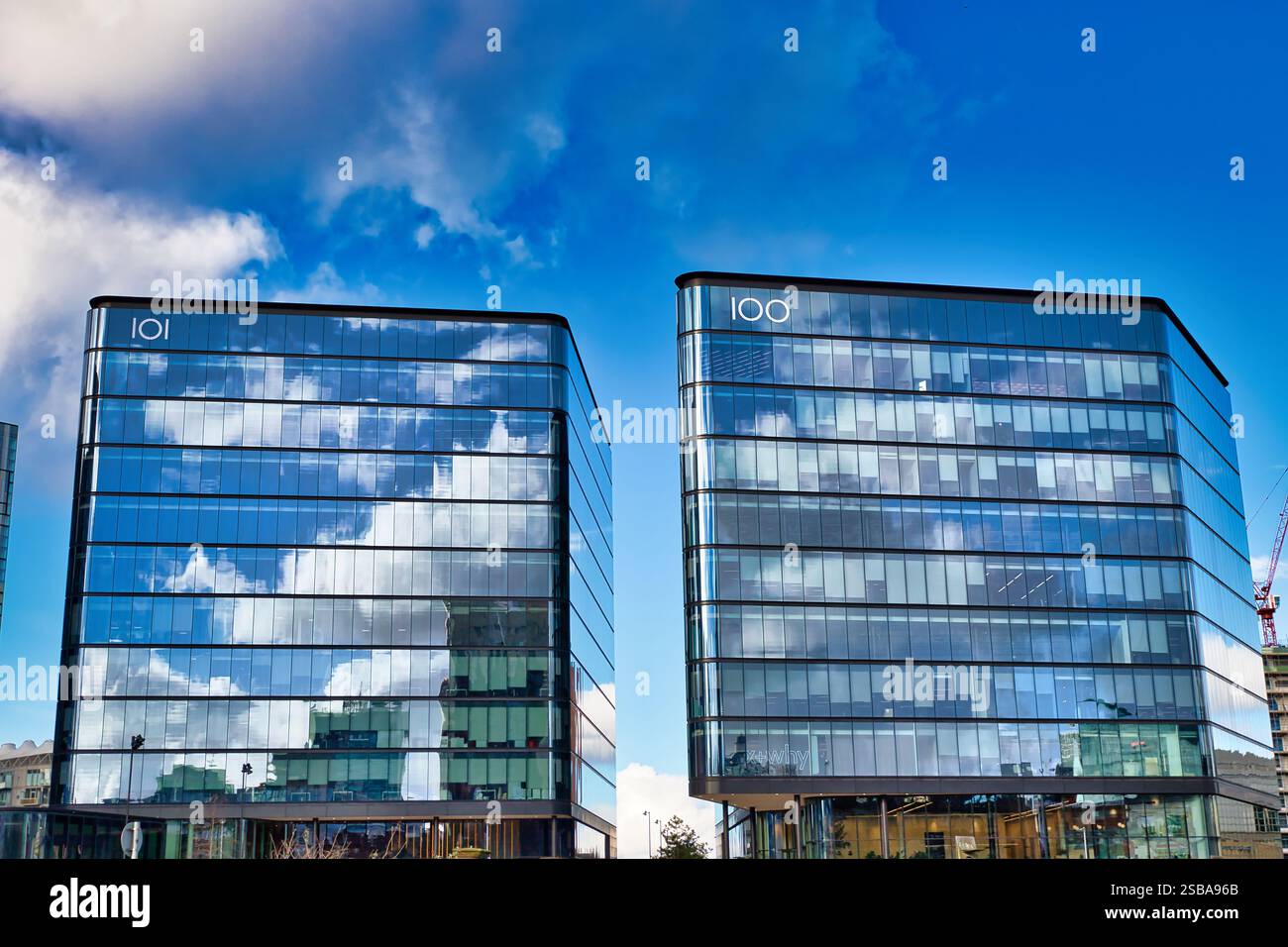 Two modern glass office buildings, numbered 101 and 100, reflect a ...