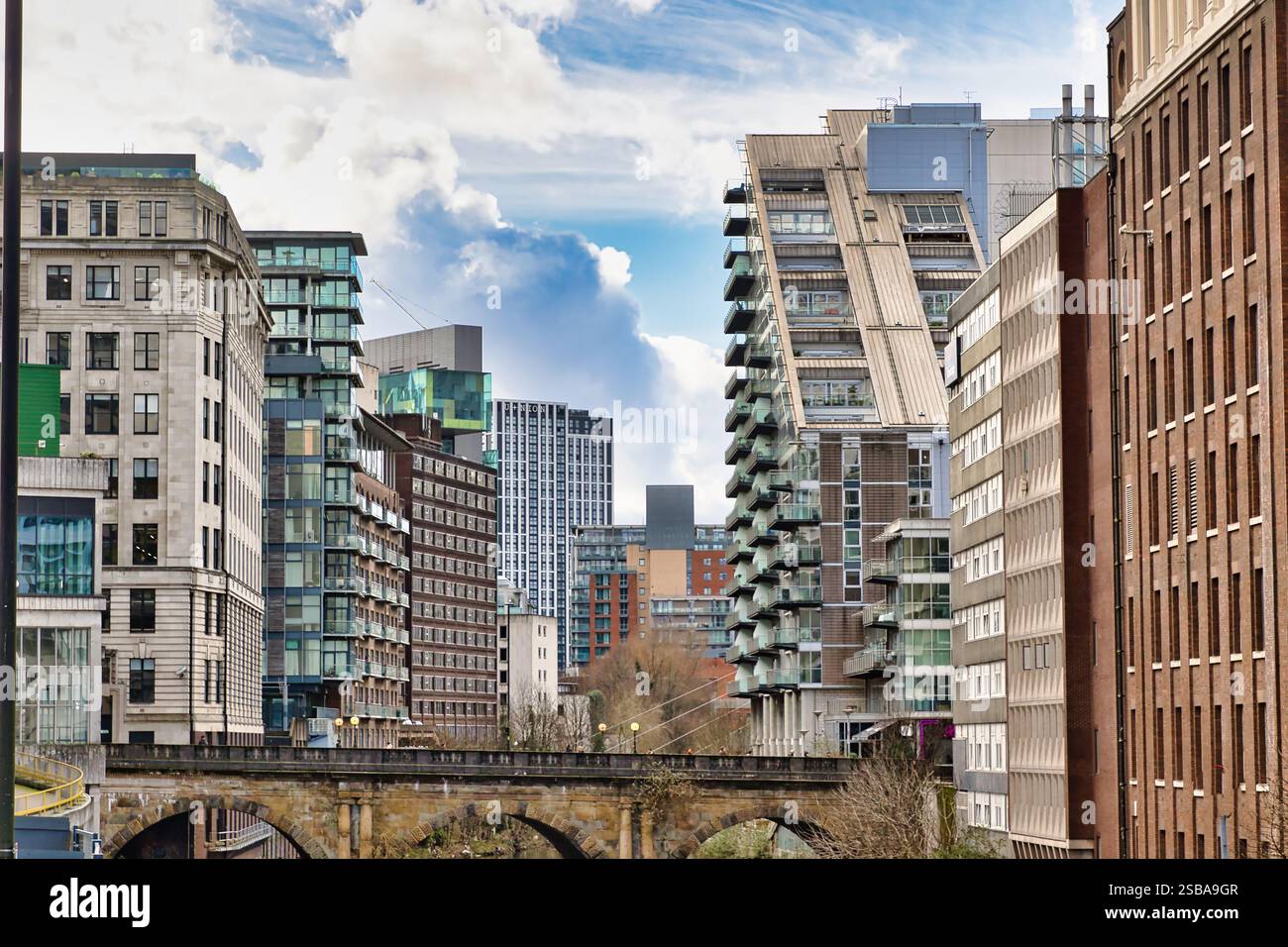 Modern and historic buildings line a waterway, viewed from a stone ...