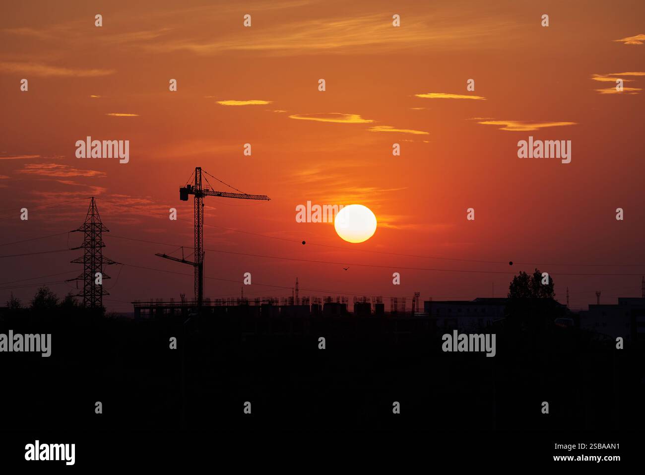 Sunset in Timisoara, Romania with cran cranes and electricity pylons ...