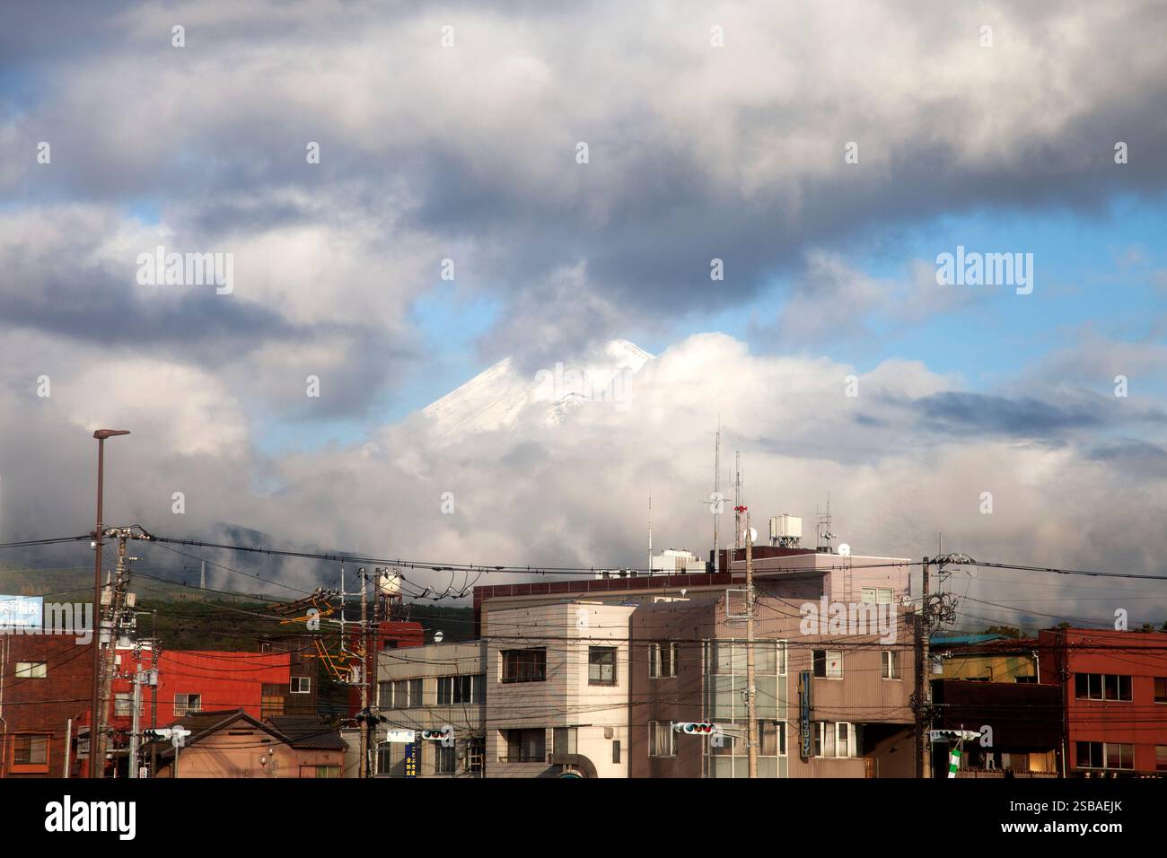 Glimpse of snow-capped Mount Fuji behind buildings and clouds near ...