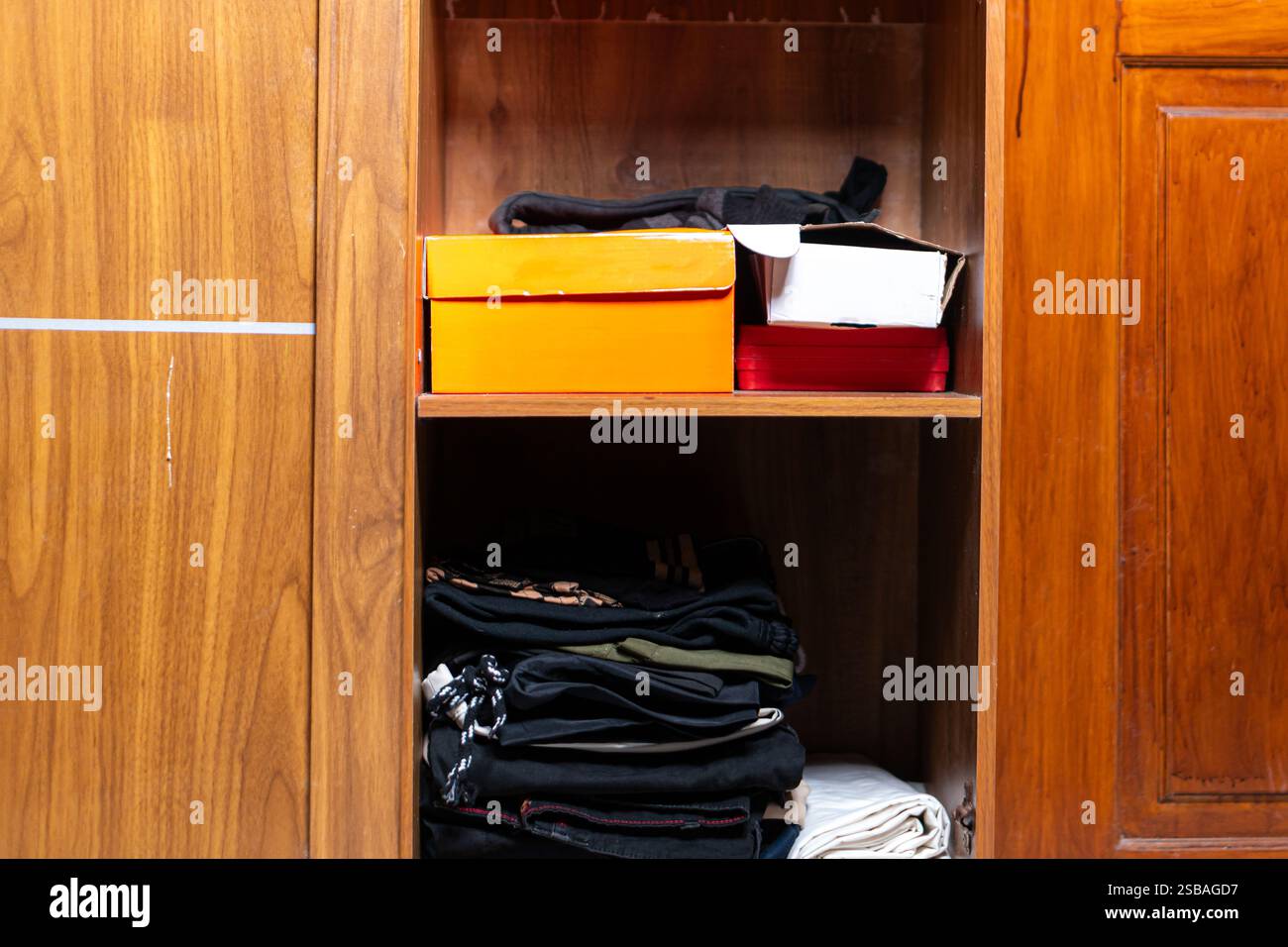 A wooden shelf with two compartments. The top compartment contains two ...