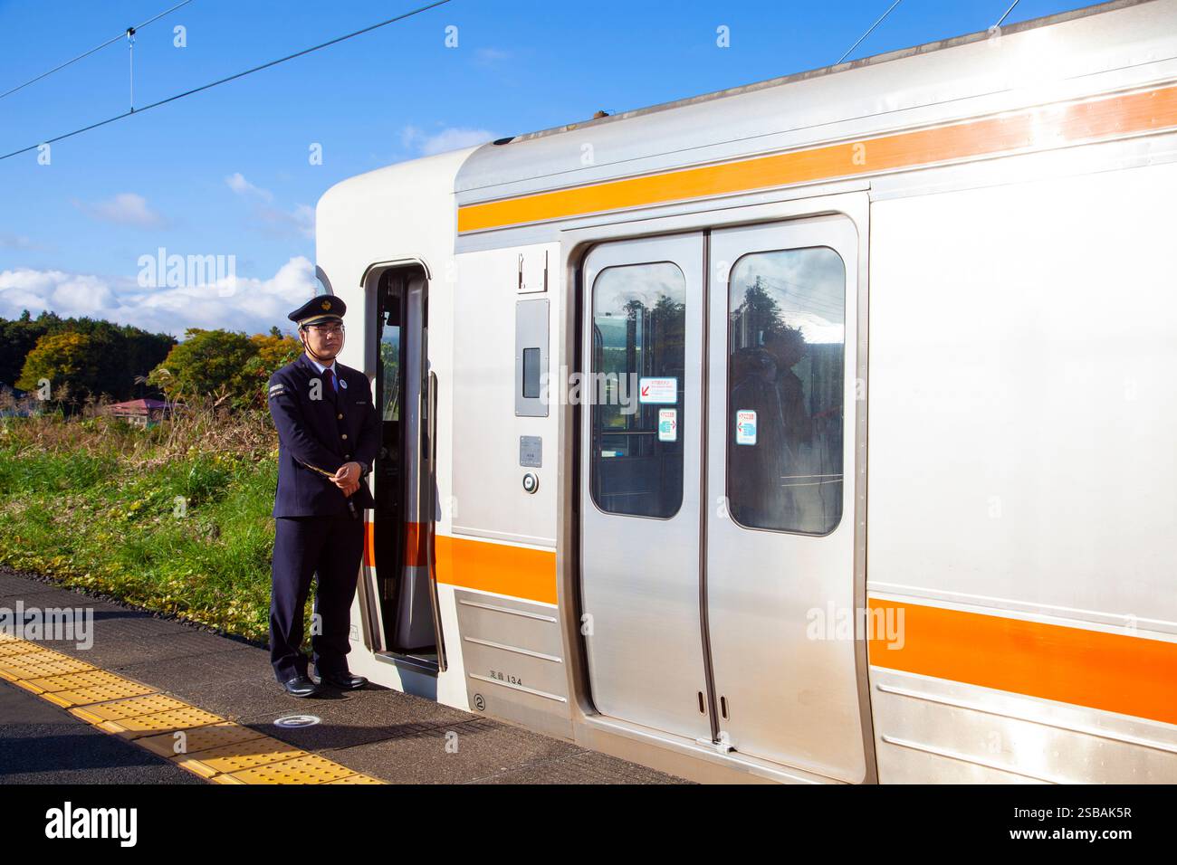 Train driver standing outside a commuter train at Fujioka train station ...