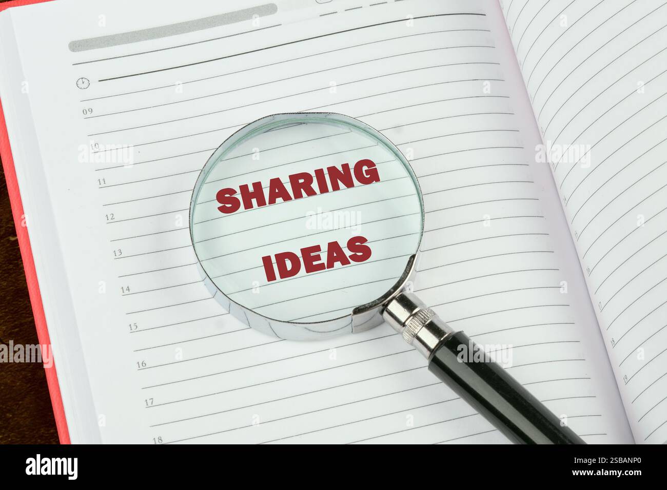 A magnifying glass emphasizes the phrase sharing ideas on a notebook ...