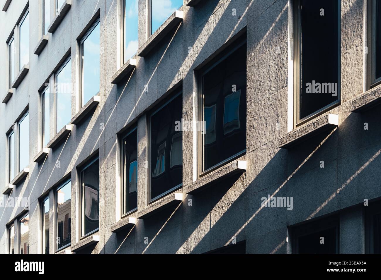 Sunlight casts dramatic shadows on the facade of a modern building ...
