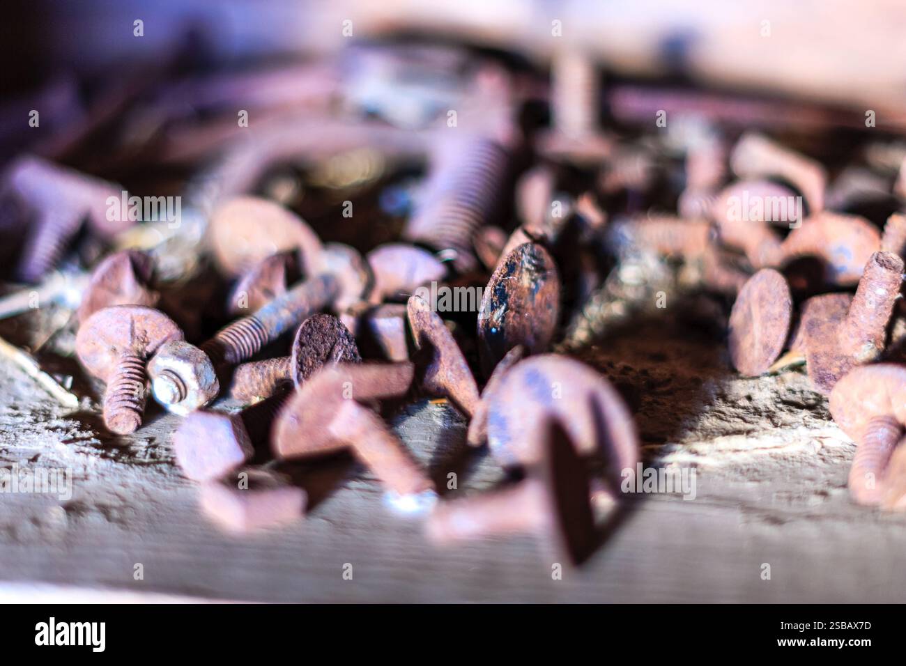 A pile of rusty screws and nails on a wooden surface. Concept of decay ...