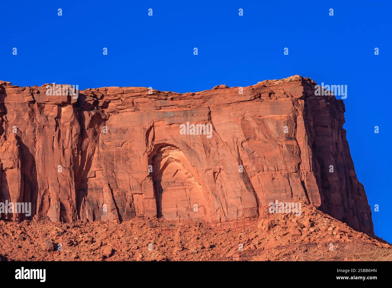 A large rock formation with a hole in the middle. The sky is blue and ...