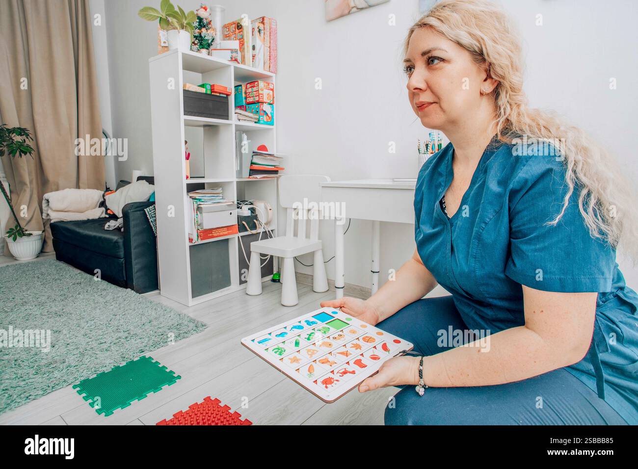therapist in a blue uniform in bright modern classroom with learning ...
