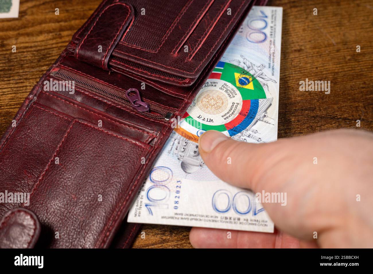 hand taking out a BRICS banknote from a wallet. Financial and economic ...