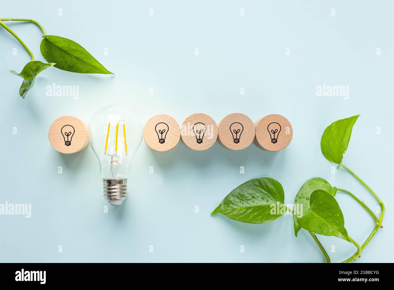 Glowing light bulb and bulb icon in round wooden block surrounded by ...