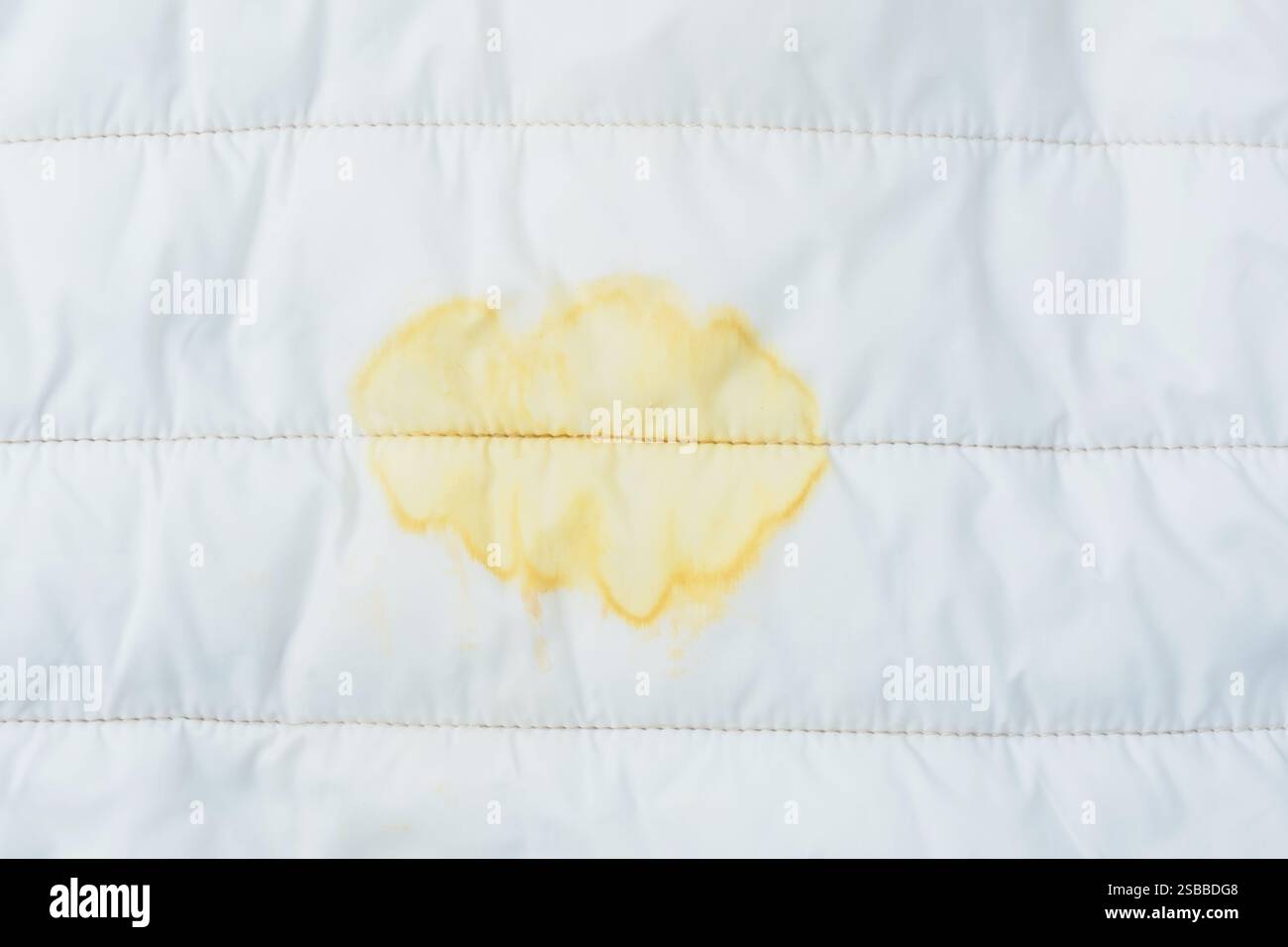 Close up white fabric or upholstery with a yellow stained. The concept ...