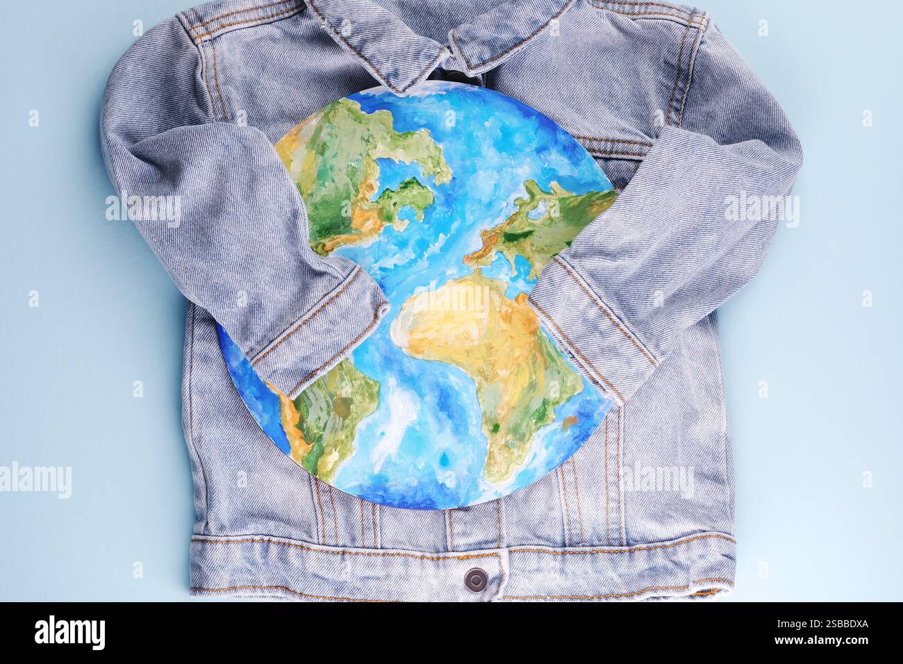Sleeves of a denim jacket embracing of the planet on a blue background ...