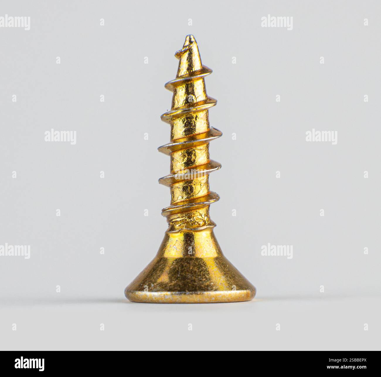 golden screw is positioned upright on a plain surface Stock Photo - Alamy