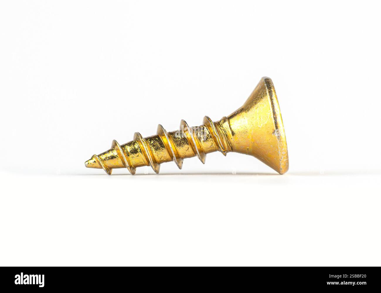 golden screw lies on a white surface ready for use in various projects ...