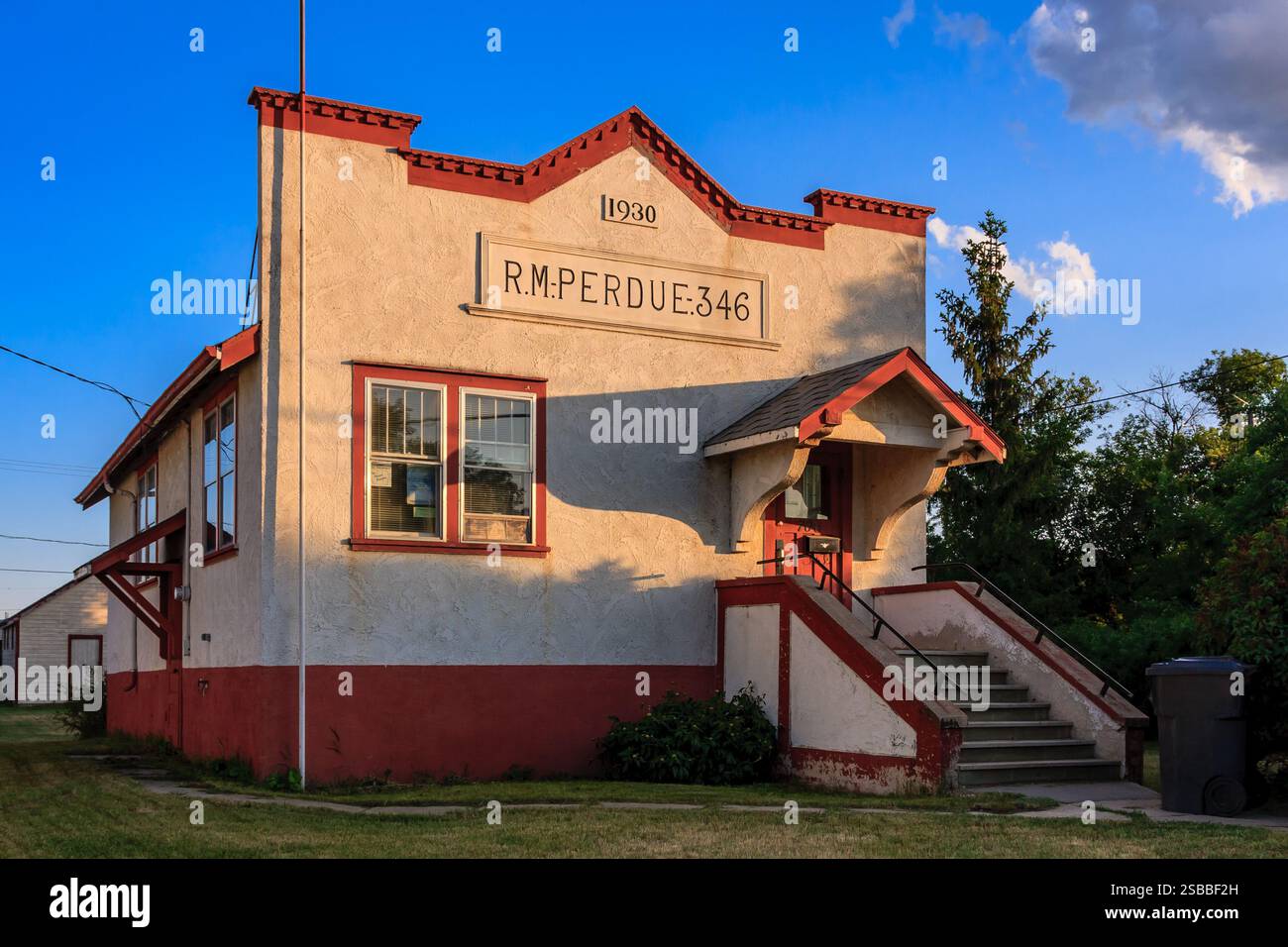 A red brick building with a white trim and a red roof. The building has ...