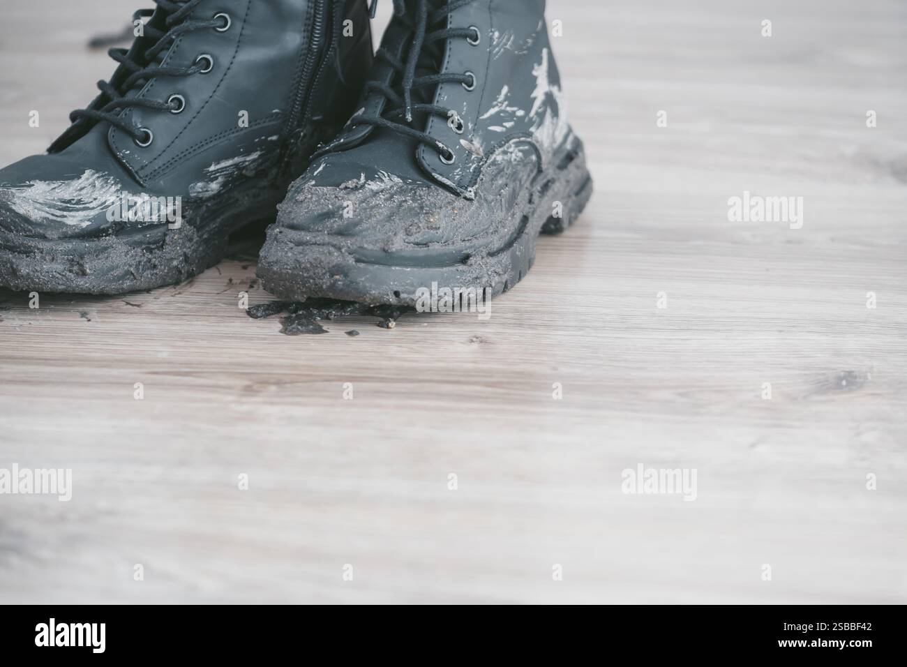 Muddy black boots and muddy footprints on a wooden floor, leaving a ...
