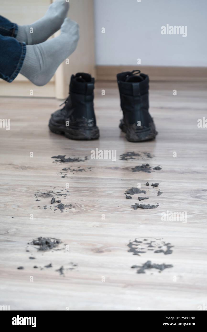 Mud Black boots next to muddy footprints on a polished wooden floor in ...