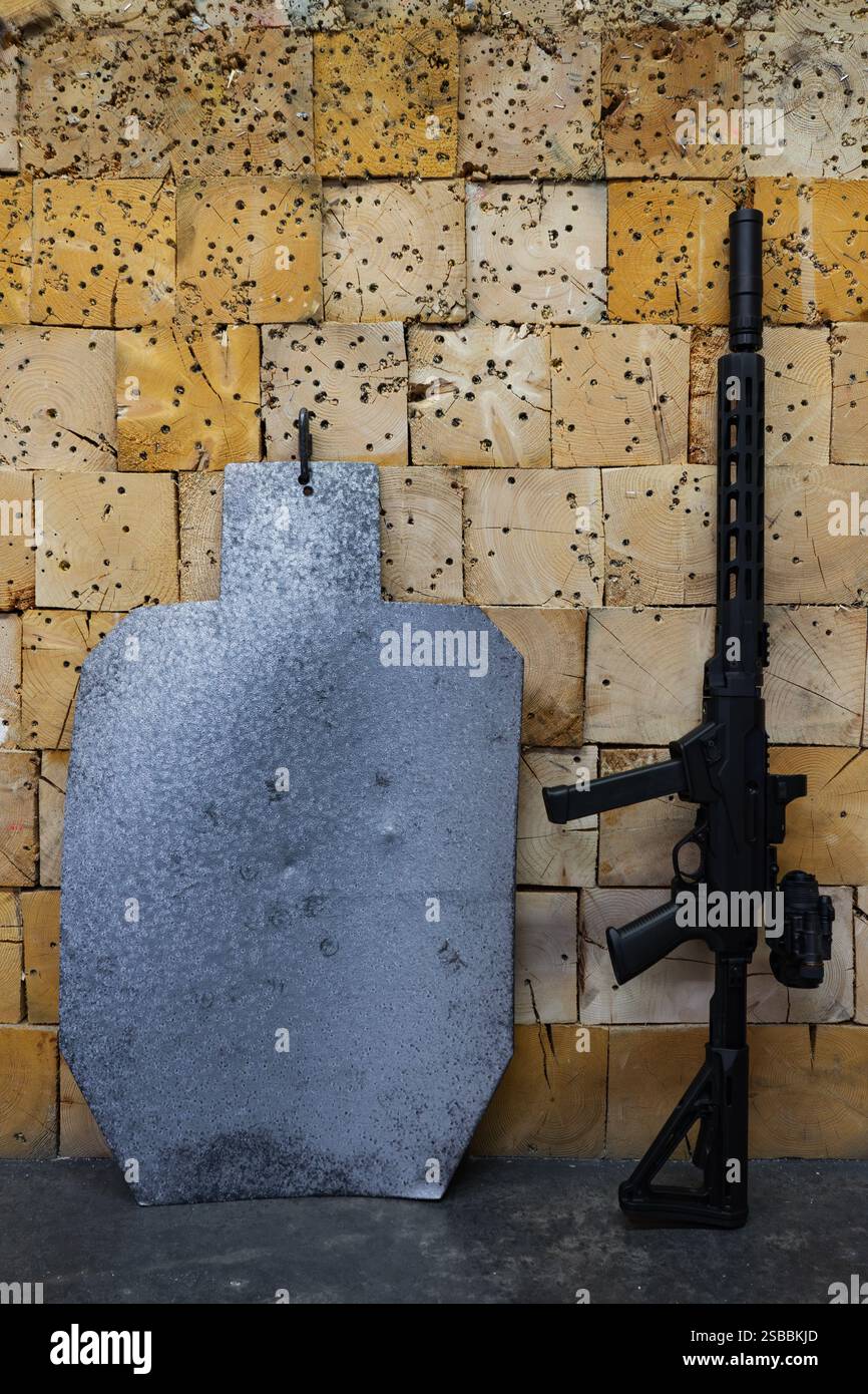 Steel target and tactical rifle with silencer in shooting range near ...