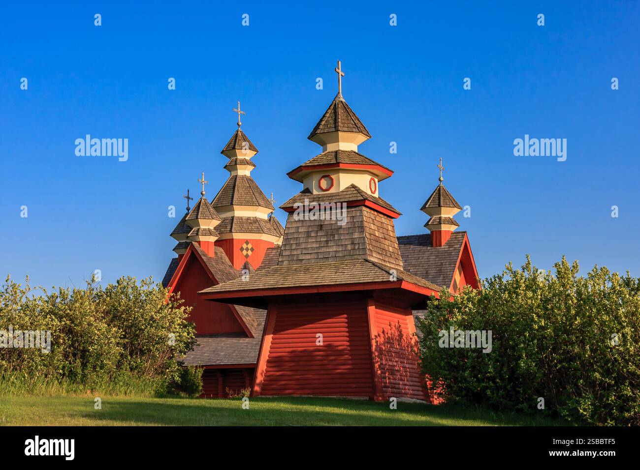 A red building with three domes and a cross on top. The building is ...