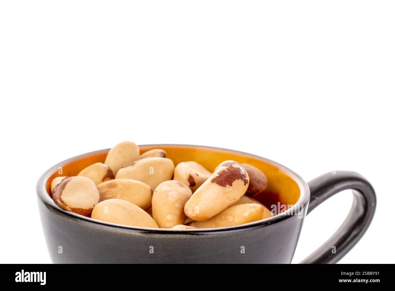 Brazil nuts without shells in a black ceramic cup, macro, isolated on ...
