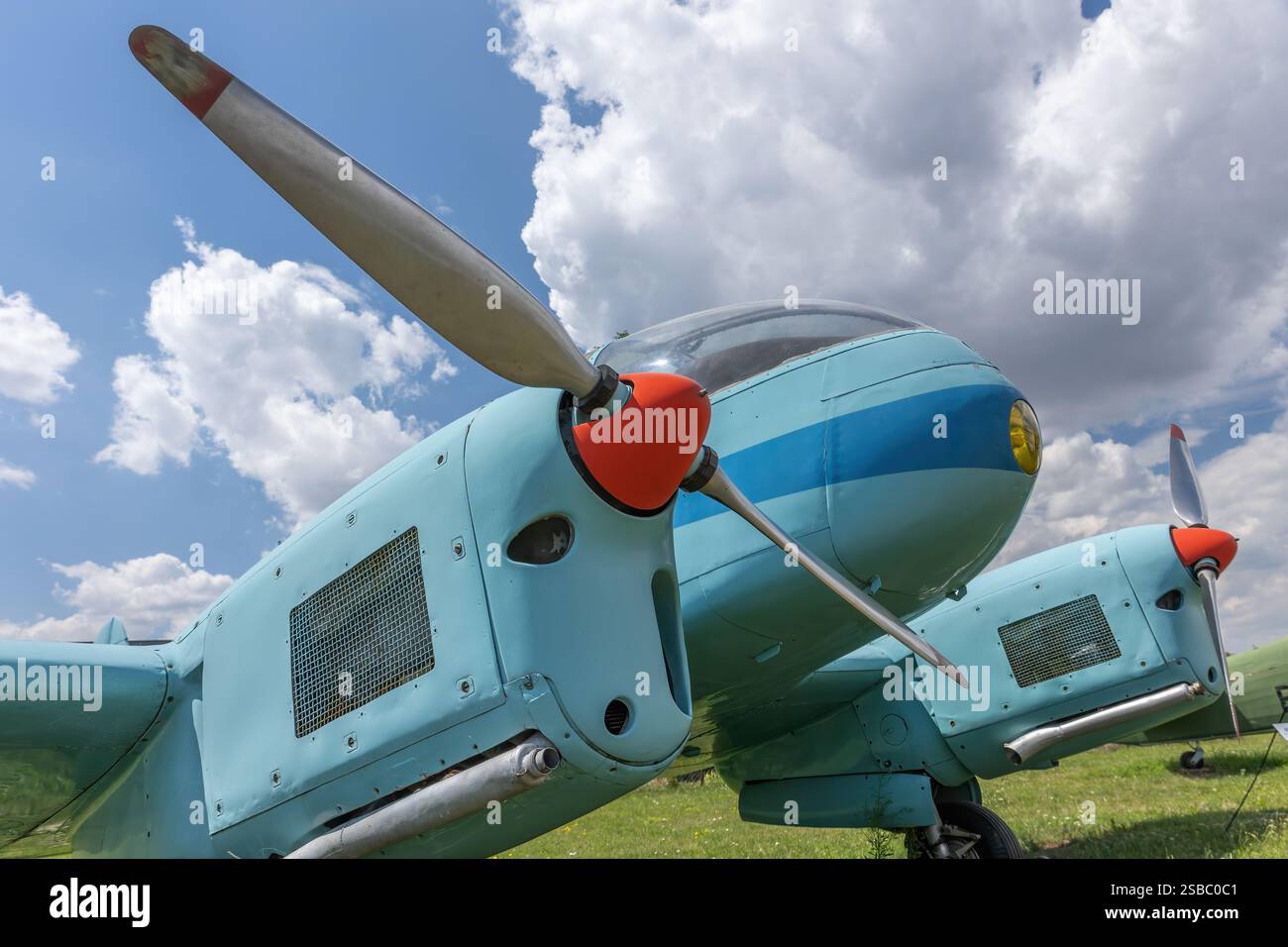 Blue propeller airplane standing on a grassy area against blue sky with ...
