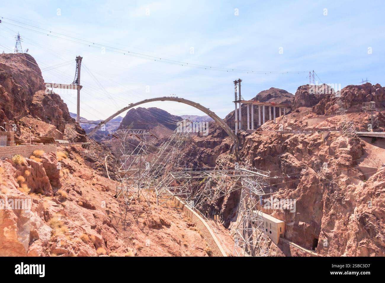 A large bridge is being constructed over a deep canyon, with a river ...