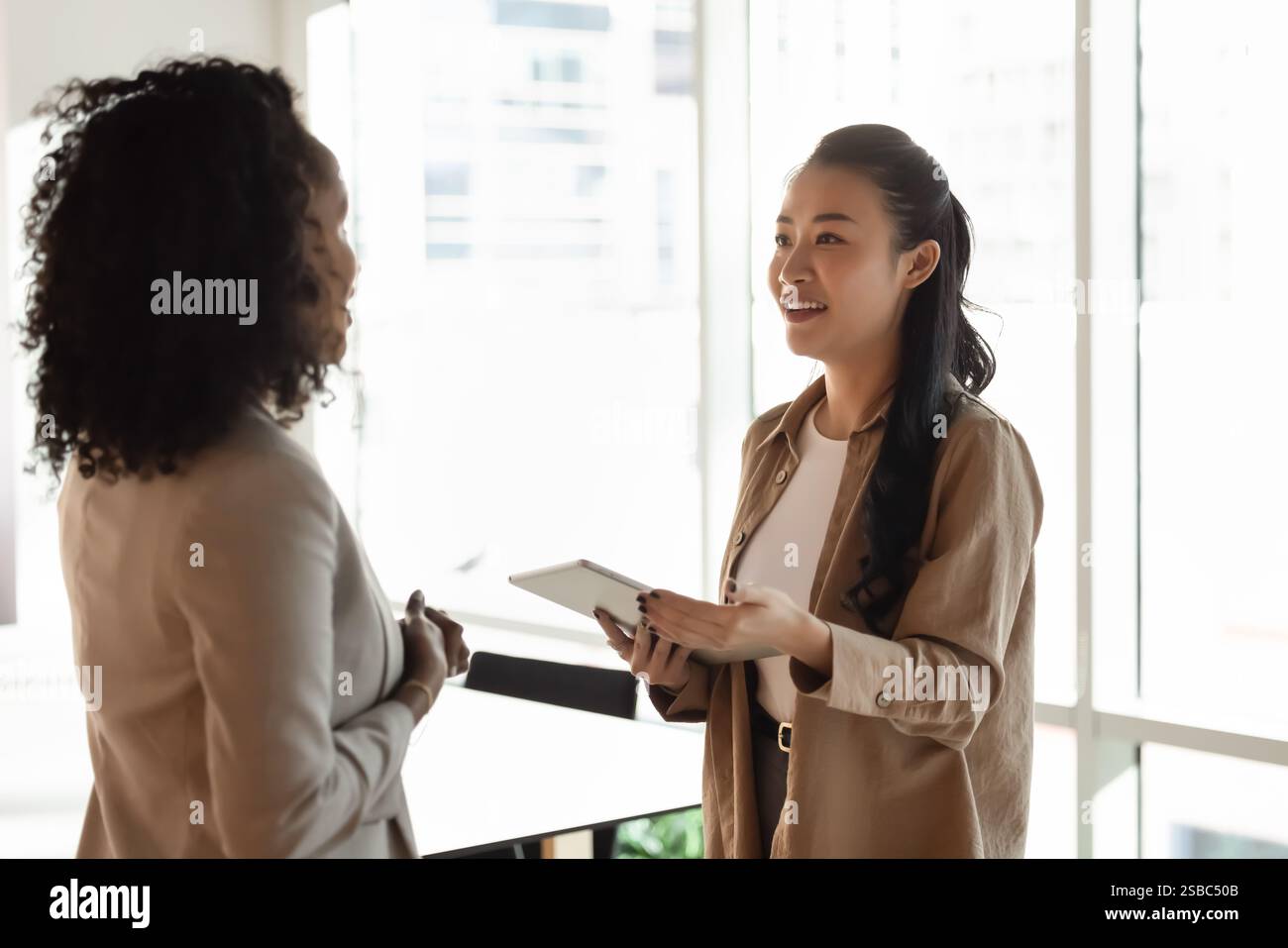 Positive young Asian employee woman asking colleague for advice Stock ...