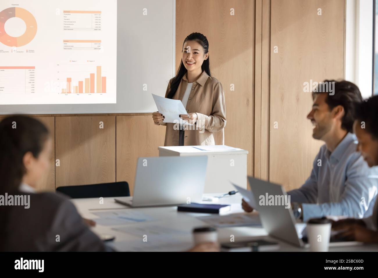 Happy young Asian speaker woman reading report to coworkers Stock Photo ...