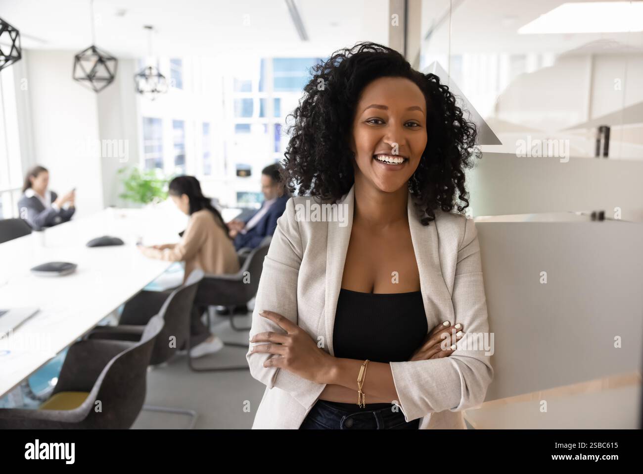 Happy beautiful female African business leader posing in meeting room ...