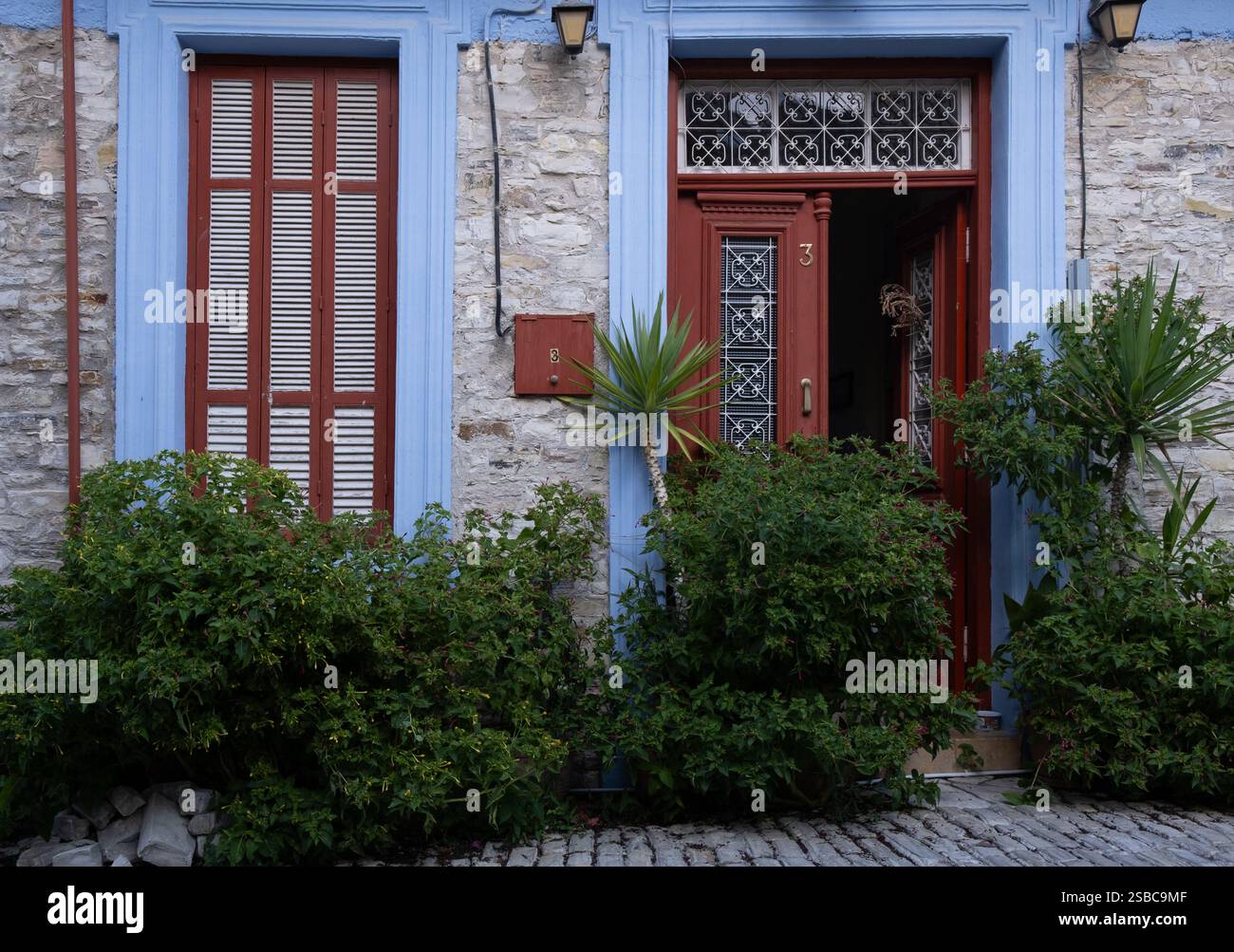 Charming traditional greek house facade with red open door, blue window ...