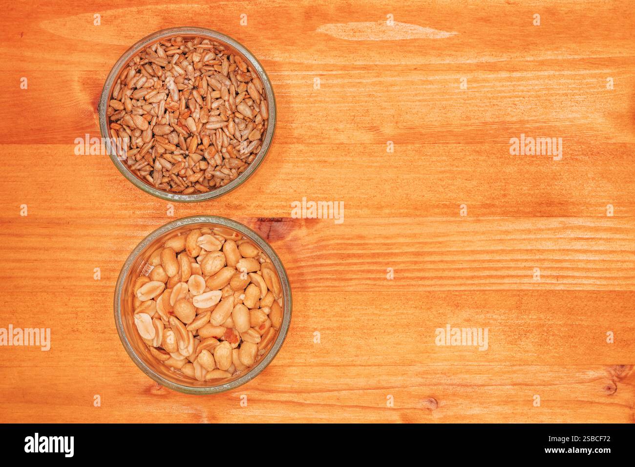 Salted peanuts and sunflower seed in glass tray on wooden table, top view Stock Photo - Alamy