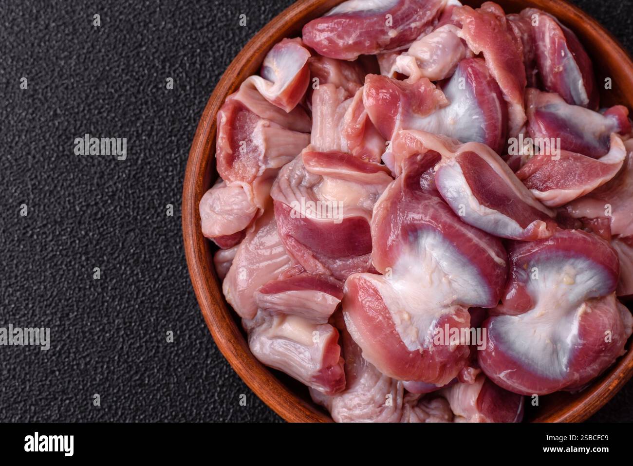Raw chicken or turkey gizzards with salt, spices and herbs on a ...