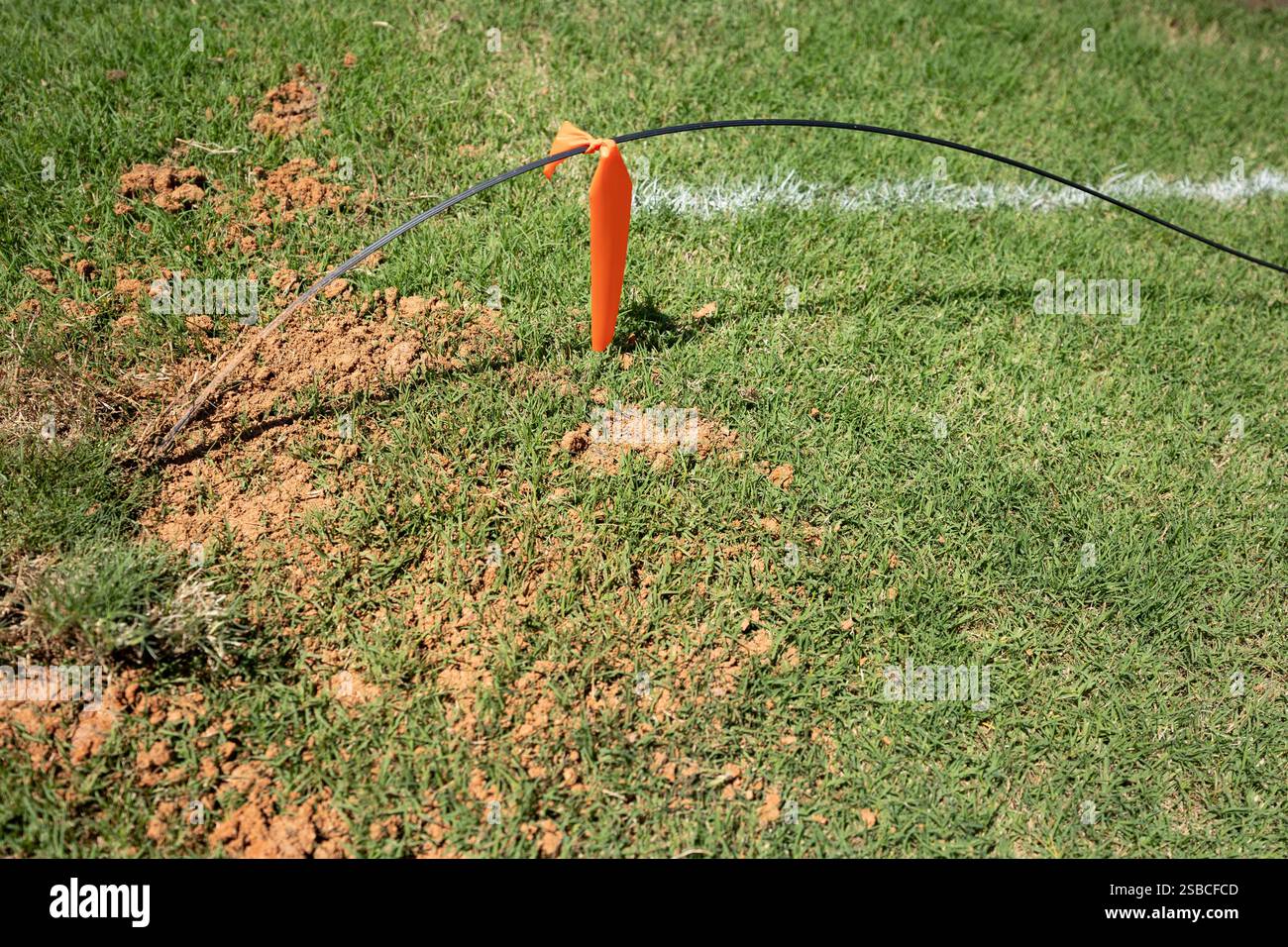 A new fiber optic cable line drop with a warning orange flag tied ...