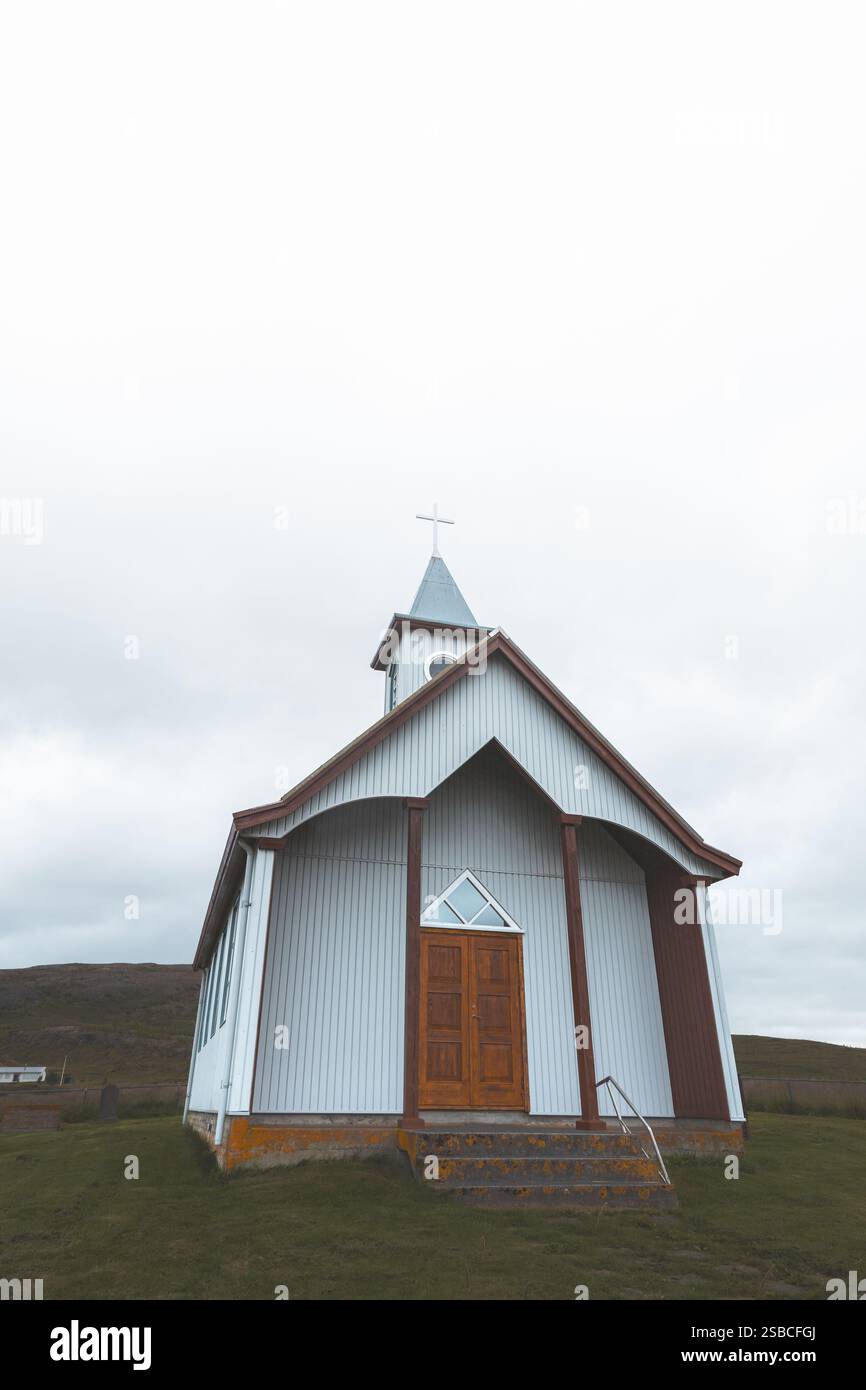 Quaint white church sits peacefully in a field in under an overcast sky ...