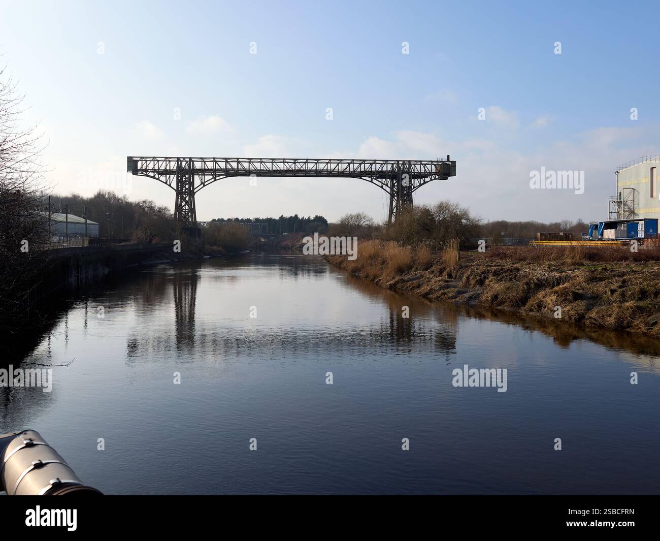 Historic industrial bridge spanning over a tranquil river landscape ...