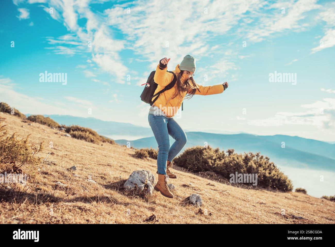 Cheering woman backpacker enjoy the view on sunrise mountain top cliff ...