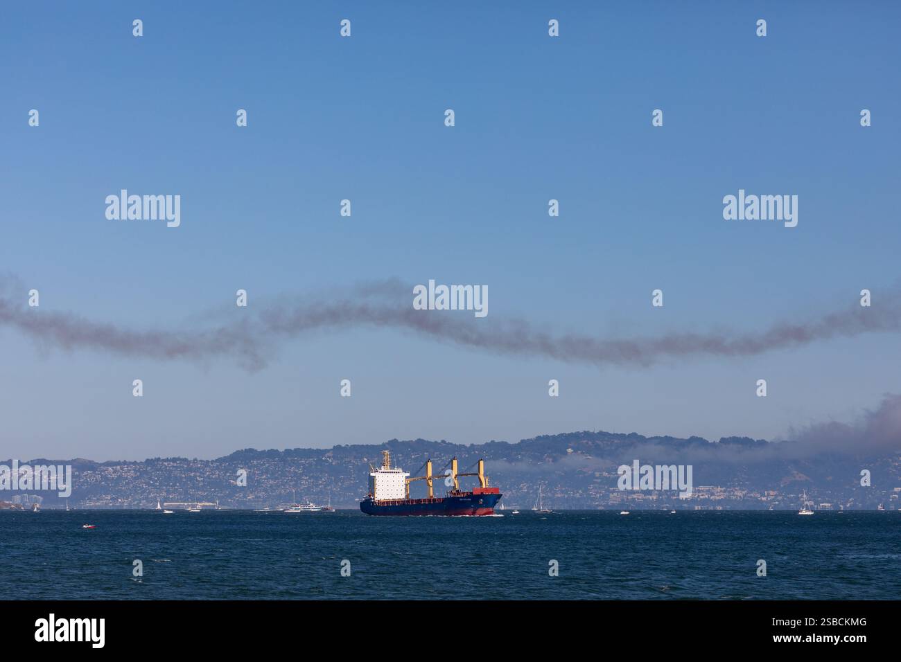 Empty cargo ship crosses under a trail of smoke exhaust leaving the San ...