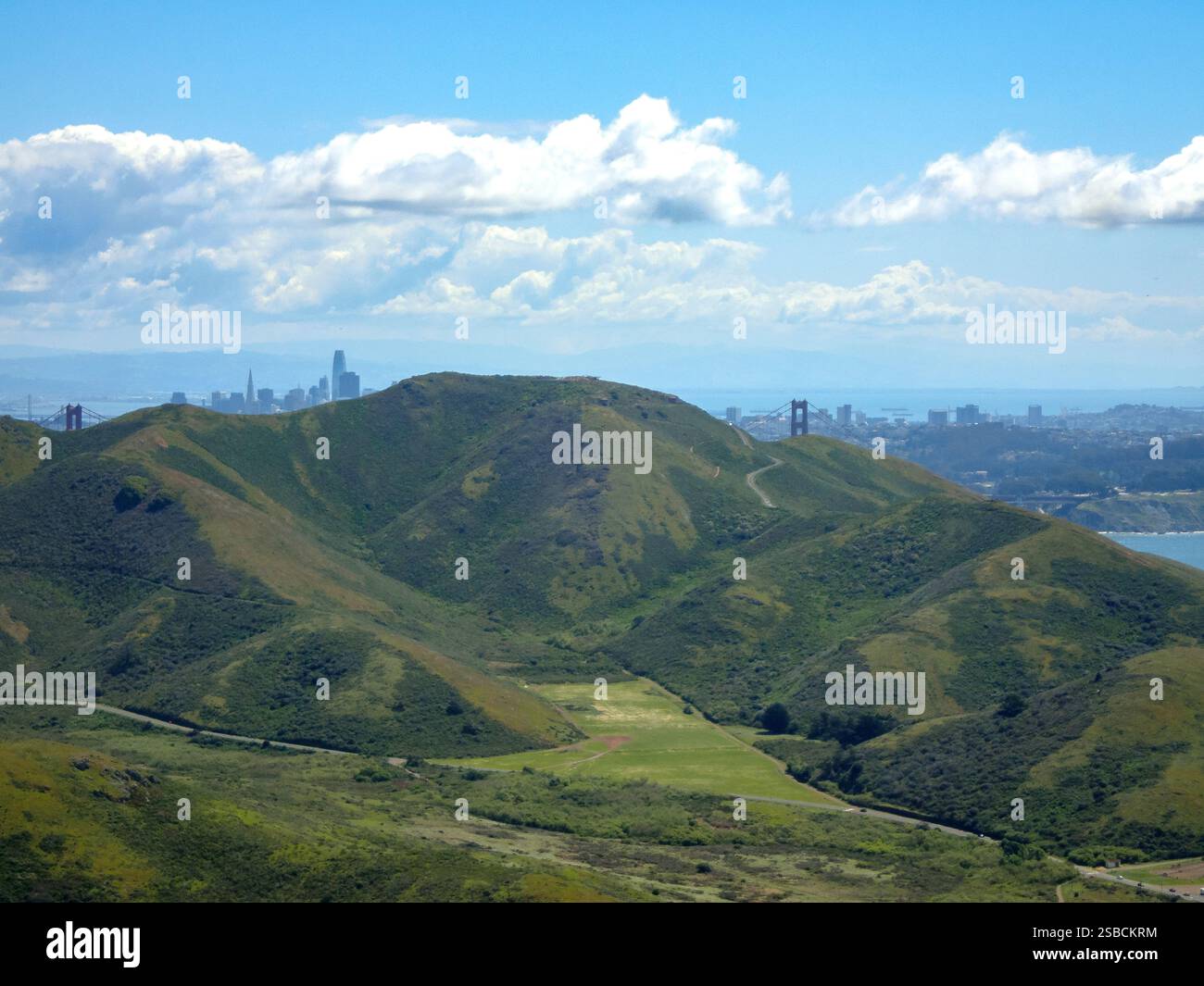 Green hills of Marin Headlands with towers of Golden Gate Bridge behind ...