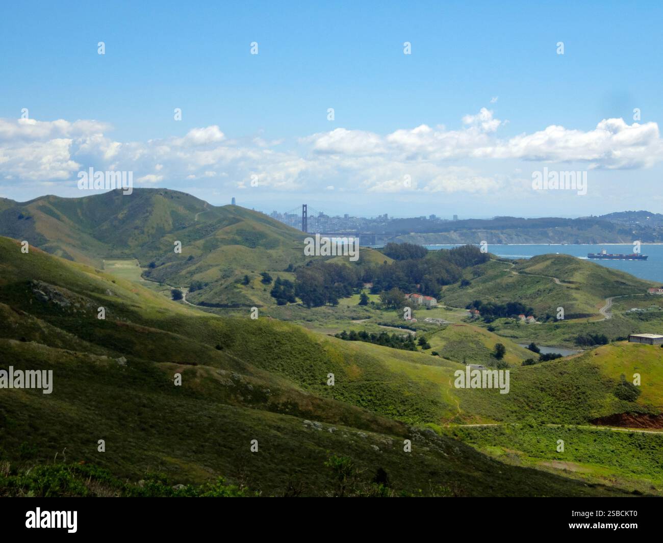 Green rolling hills of Marin Headlands with tower of Golden Gate Bridge ...