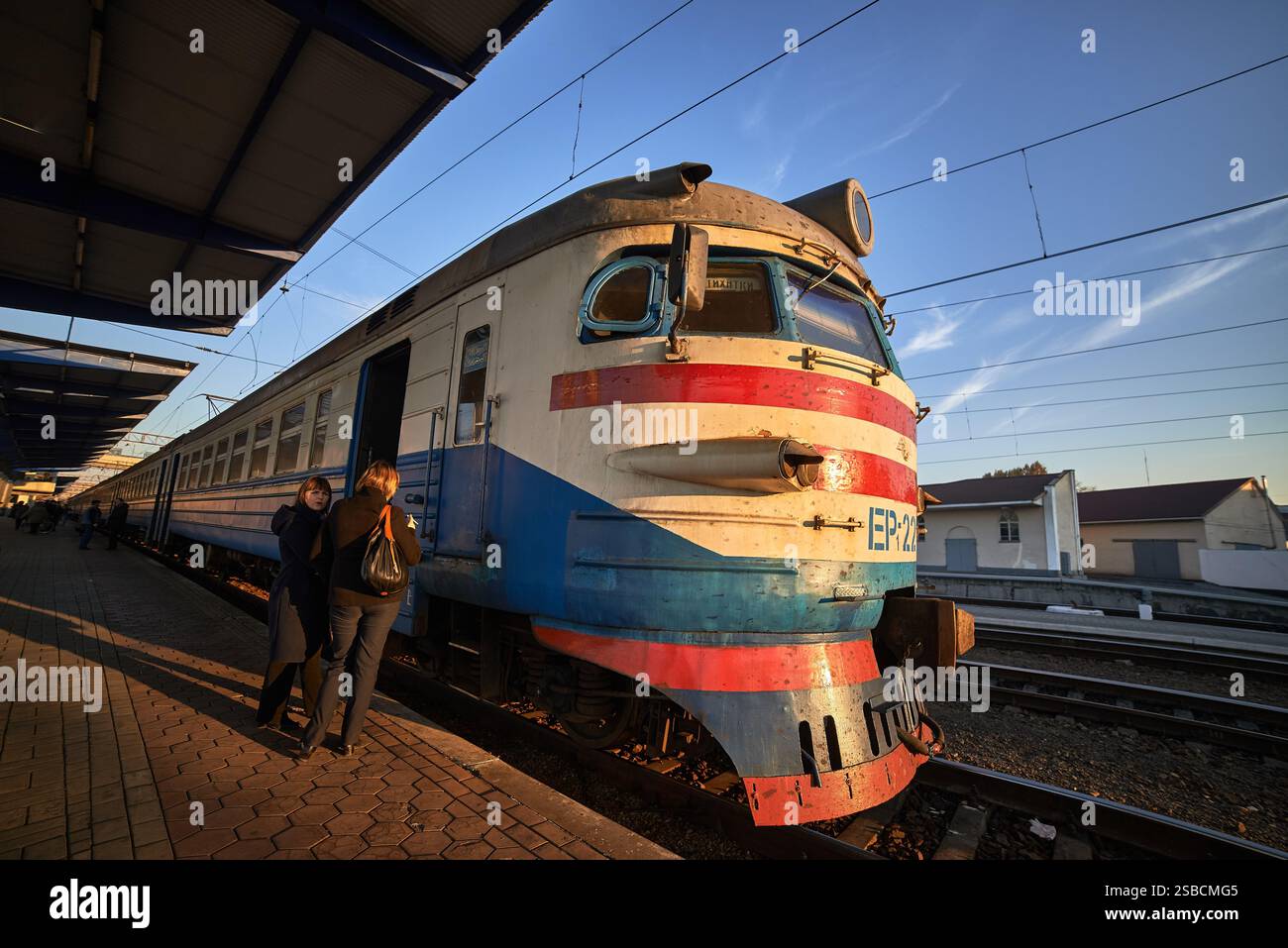 Old locomotive at sunny railway station platform with travelers, retro ...