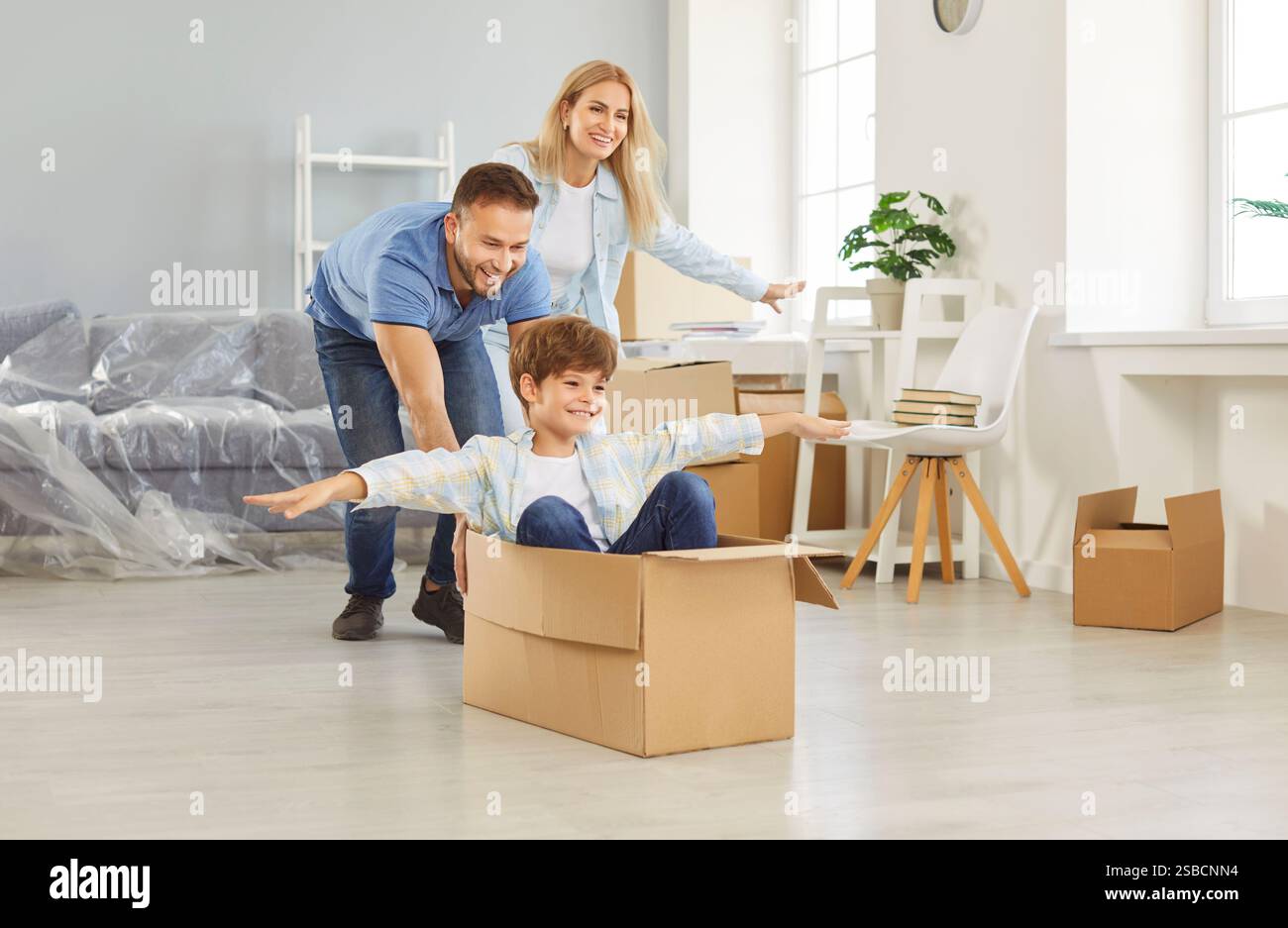 Joyful young family playing together as parents pushing their son in ...