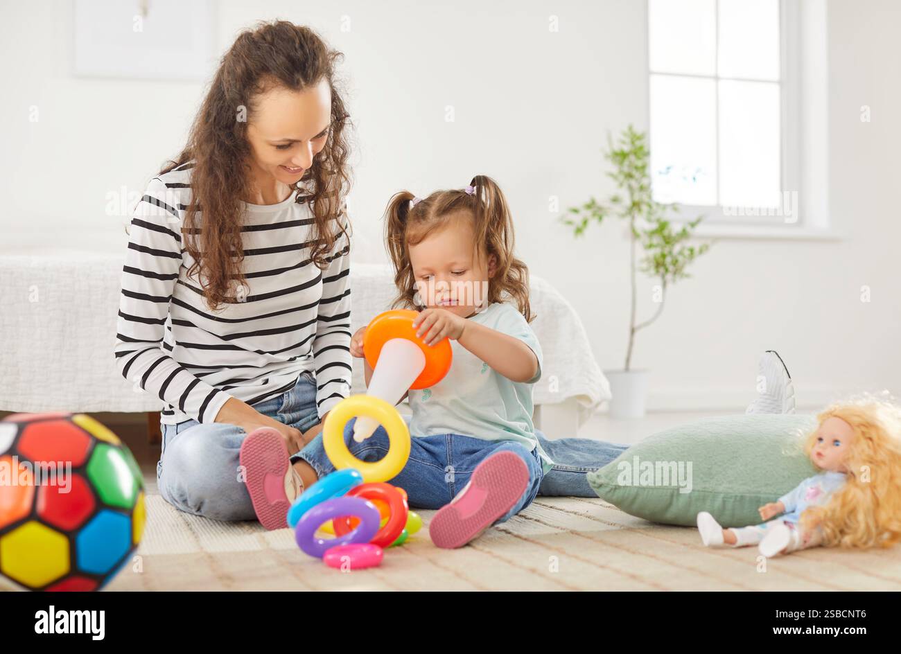 Mother with little child girl playing together with kids toys sitting ...